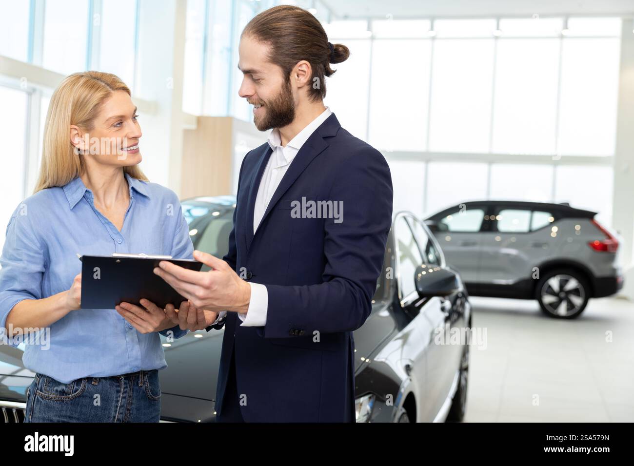 Blonde female customer signing the contract with dealership ...