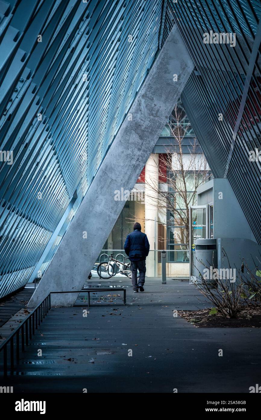 A moody urban scene featuring architectural details of the Seattle Public Library downtown, with ...