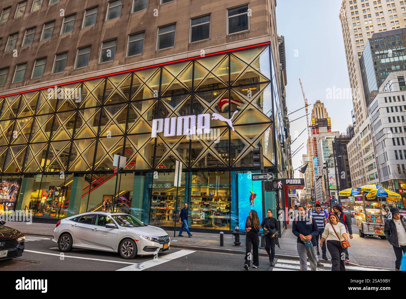Puma flagship store with modern glass facade and pedestrians in busy New York City street. New ...