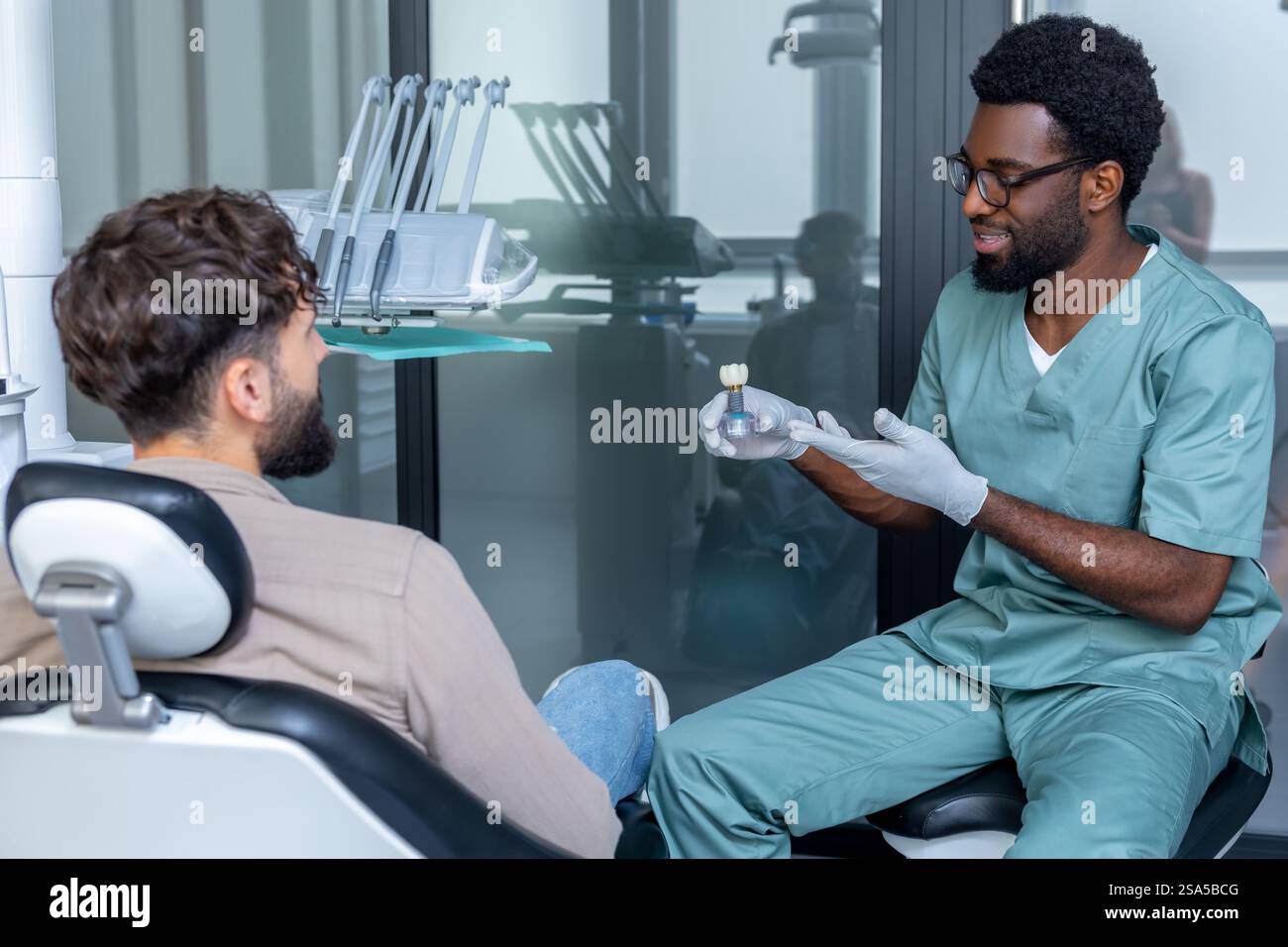 Male stomatologist with patient during dental visit before implanting ...