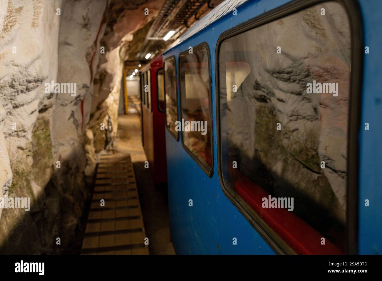 A blue train in a rocky tunnel, showcasing unique engineering and ...