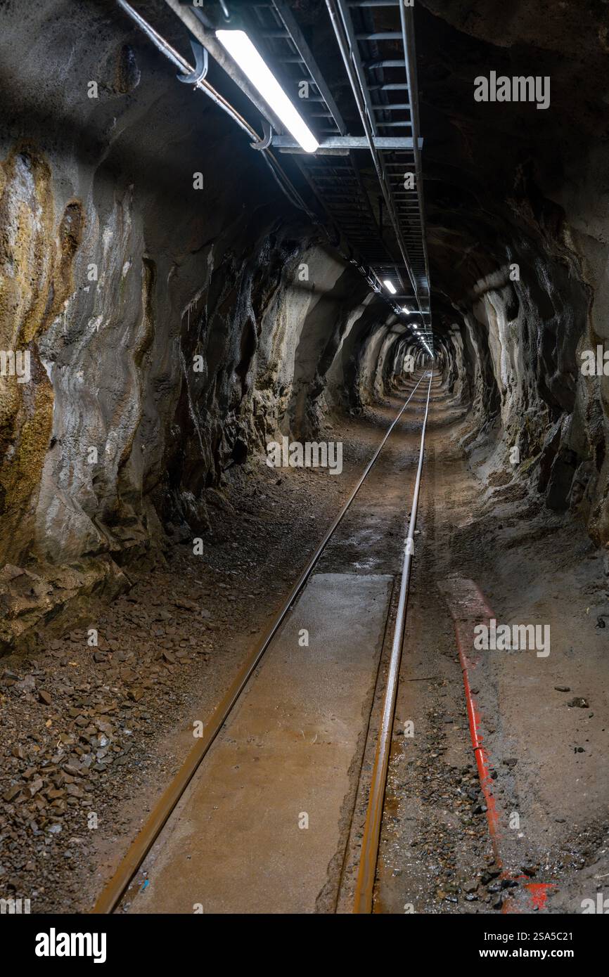 An underground tunnel featuring train tracks running through a rugged ...