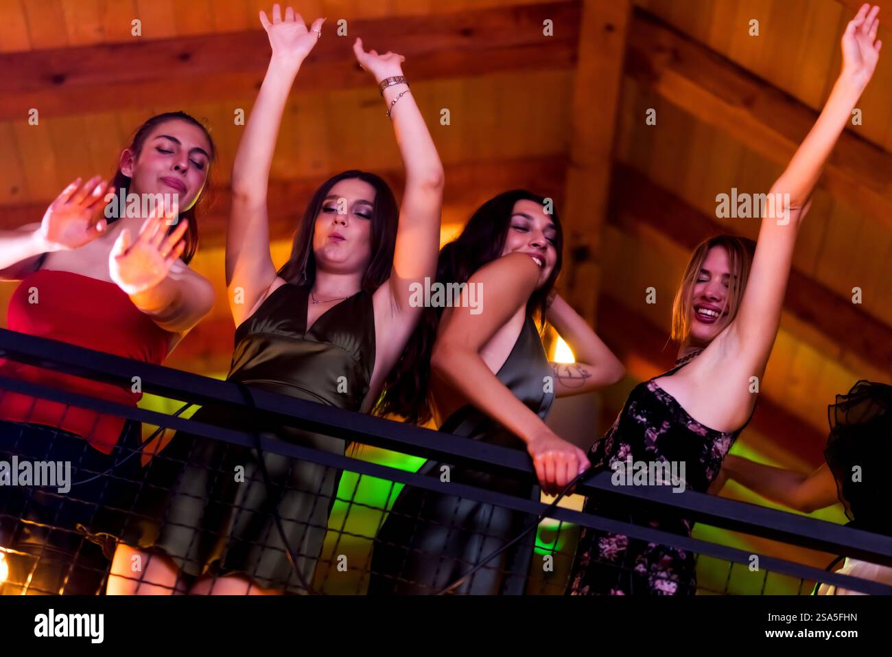 Four young women joyfully dancing at a party, sharing laughter and ...