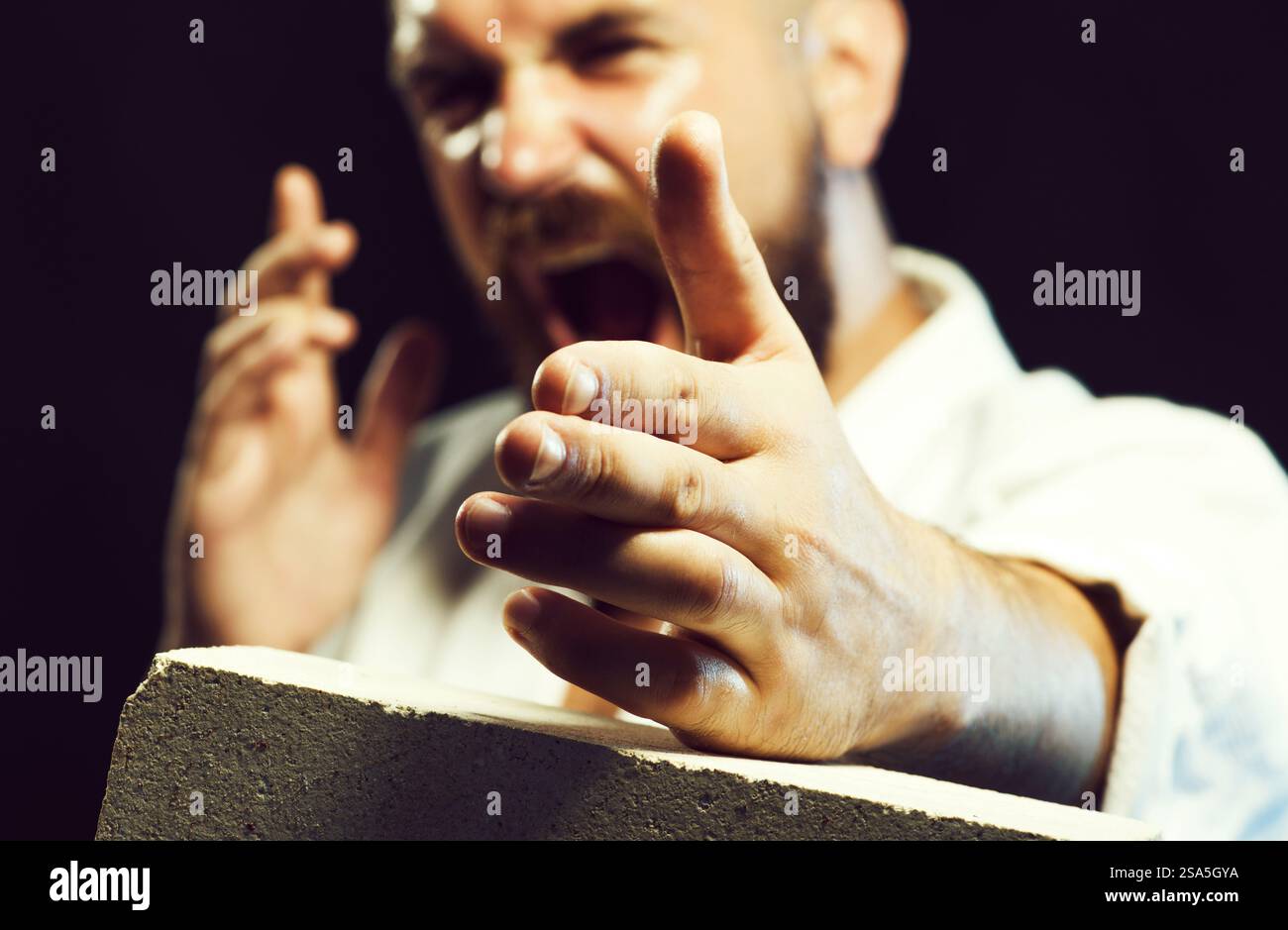 Man hand breaking concrete brick. Strong karate man in white kimono ...