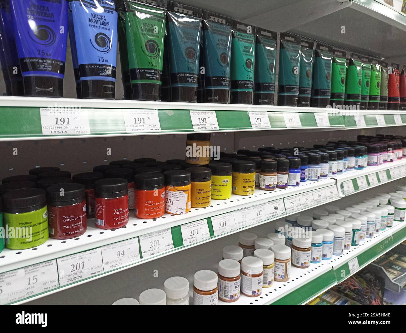 Assorted art supplies display on store shelves with paint tubes and ...