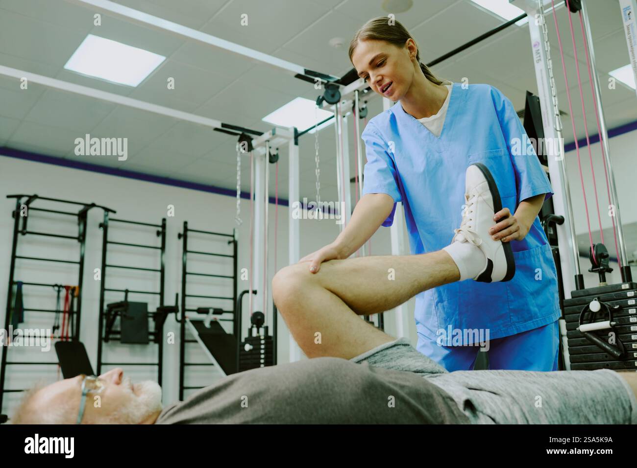 Low angle shot of female trainer teaching elderly patient how to ...