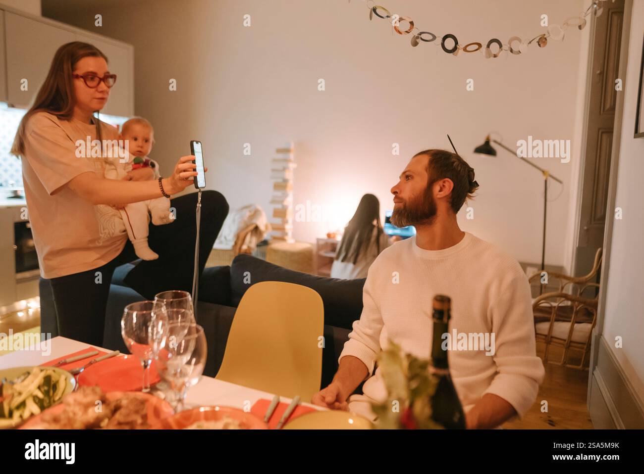 A family gathering with a joyful baby and a festive dinner setting ...