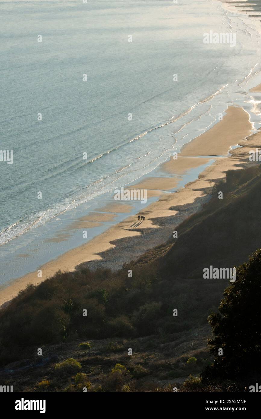 Three people enjoy a peaceful walk along Swanage Beach in Purbeck as ...
