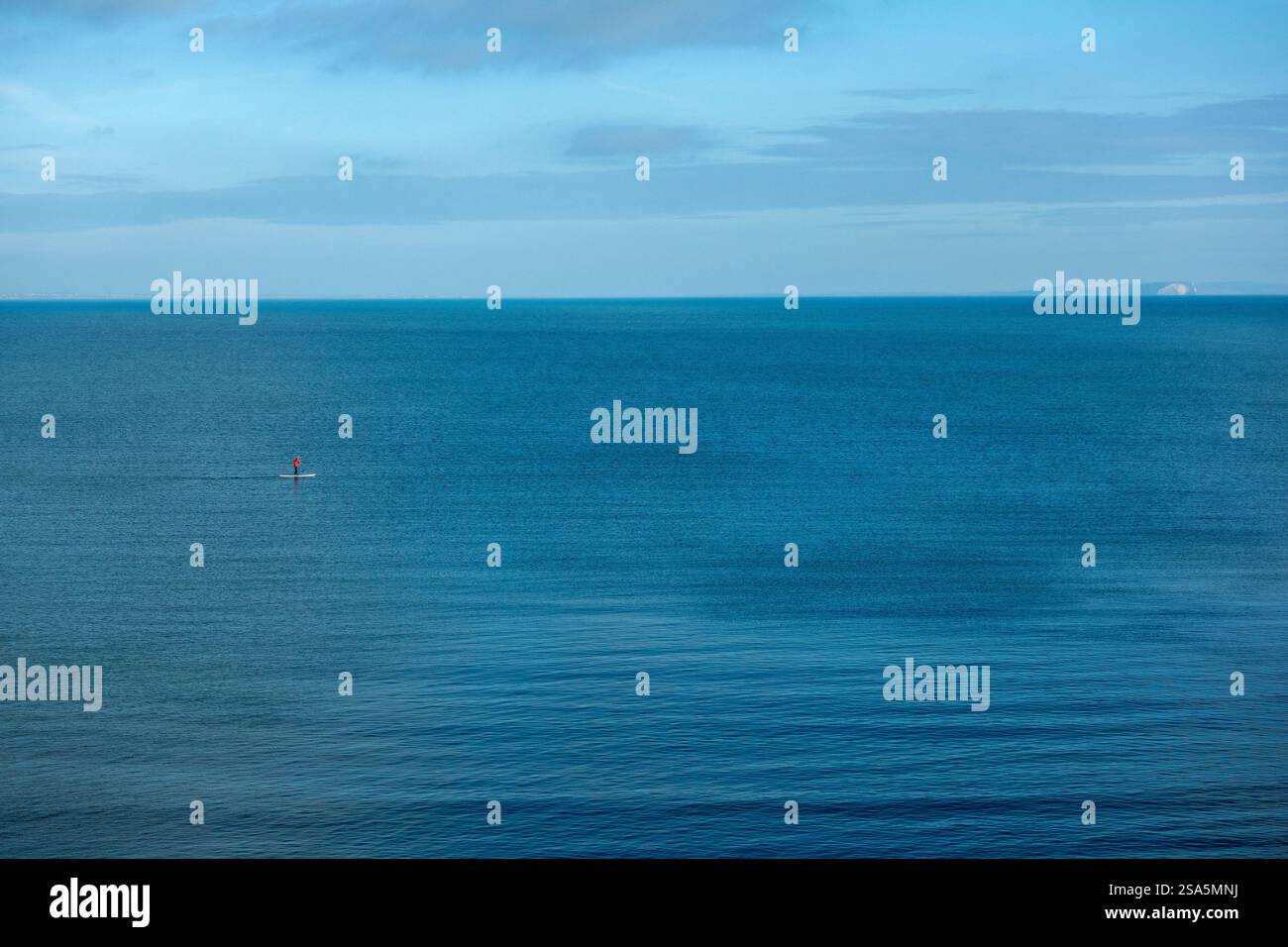 Lone paddleboarder glides across calm waters with the Isle of Wight in ...
