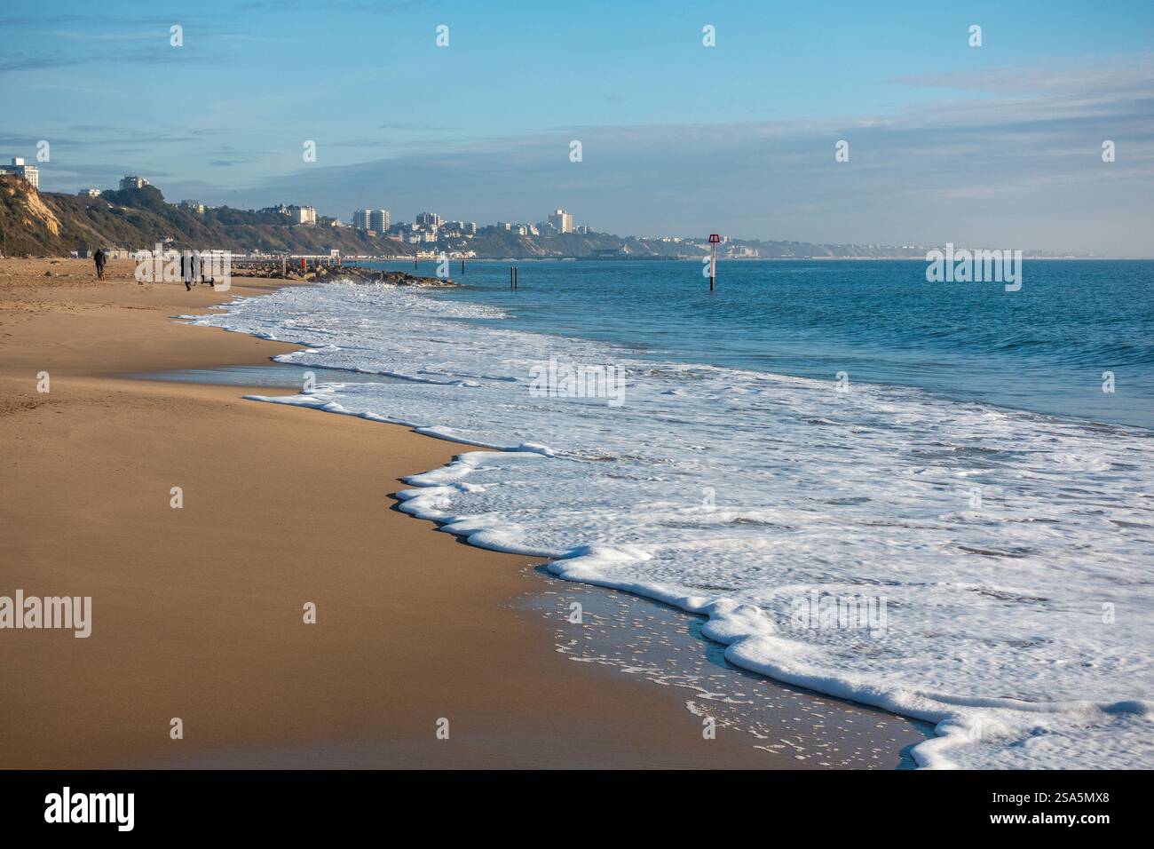 People stroll along the sandy shores of Branksome beach in Bournemouth ...