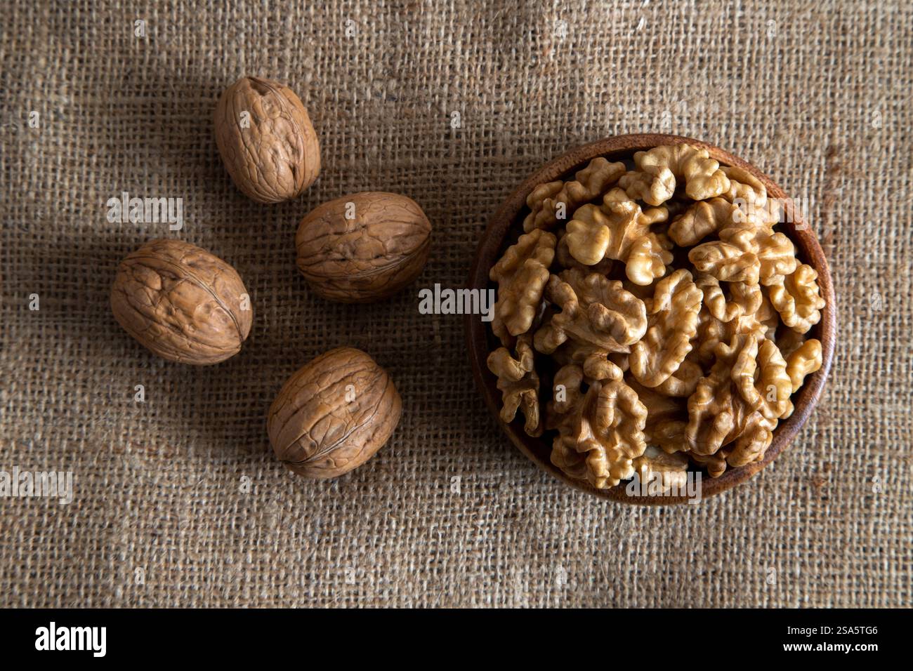 A wooden bowl filled with walnut kernels, placed alongside whole ...