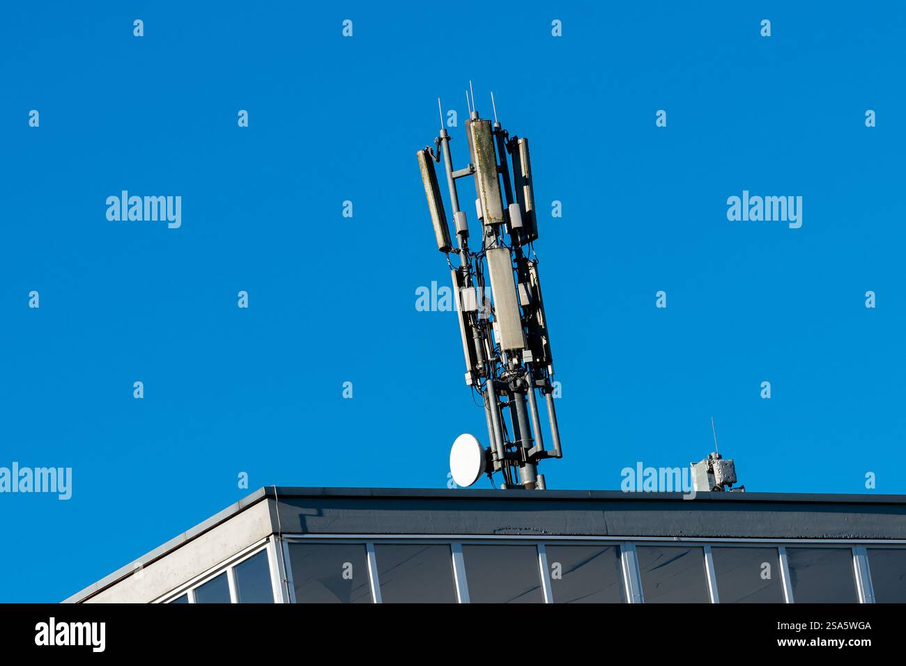 A cell tower and satellite dish are positioned on the rooftop of a ...