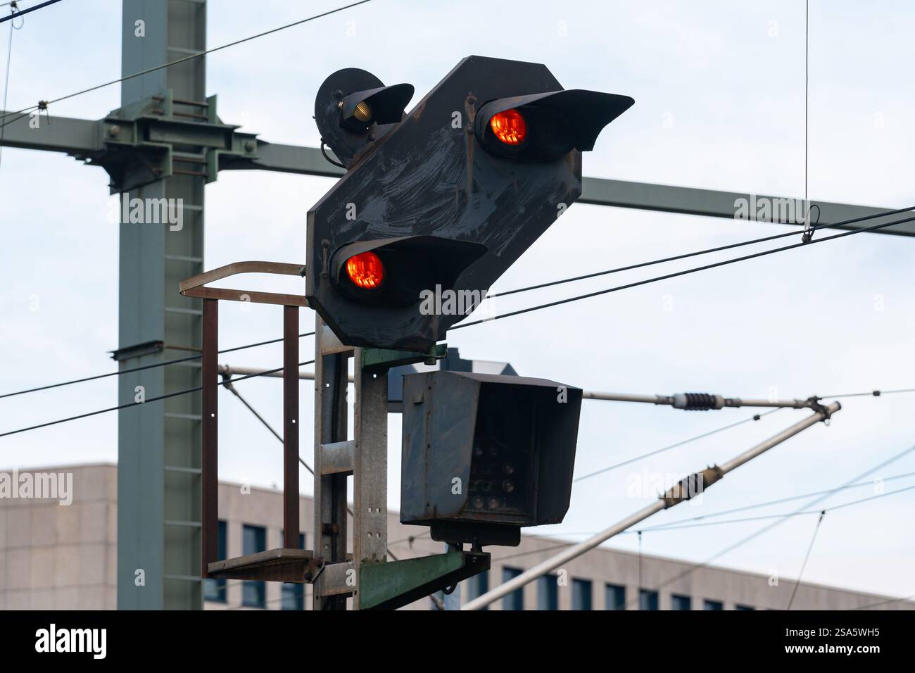 A railroad signal shows red lights indicating caution along a track in ...