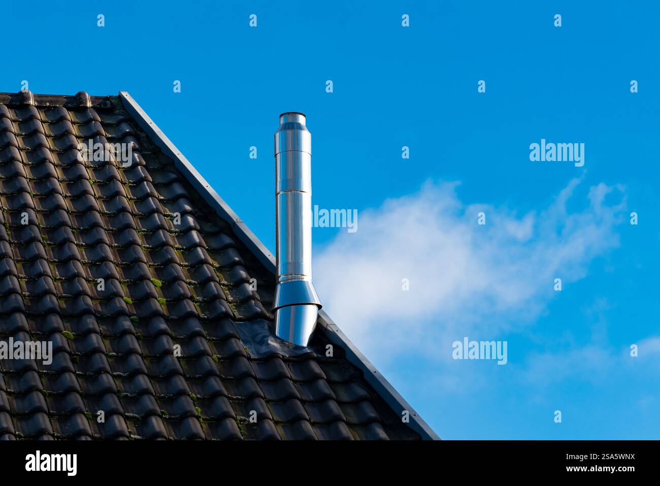 A metal chimney rises from a pitched roof, showcasing modern ...