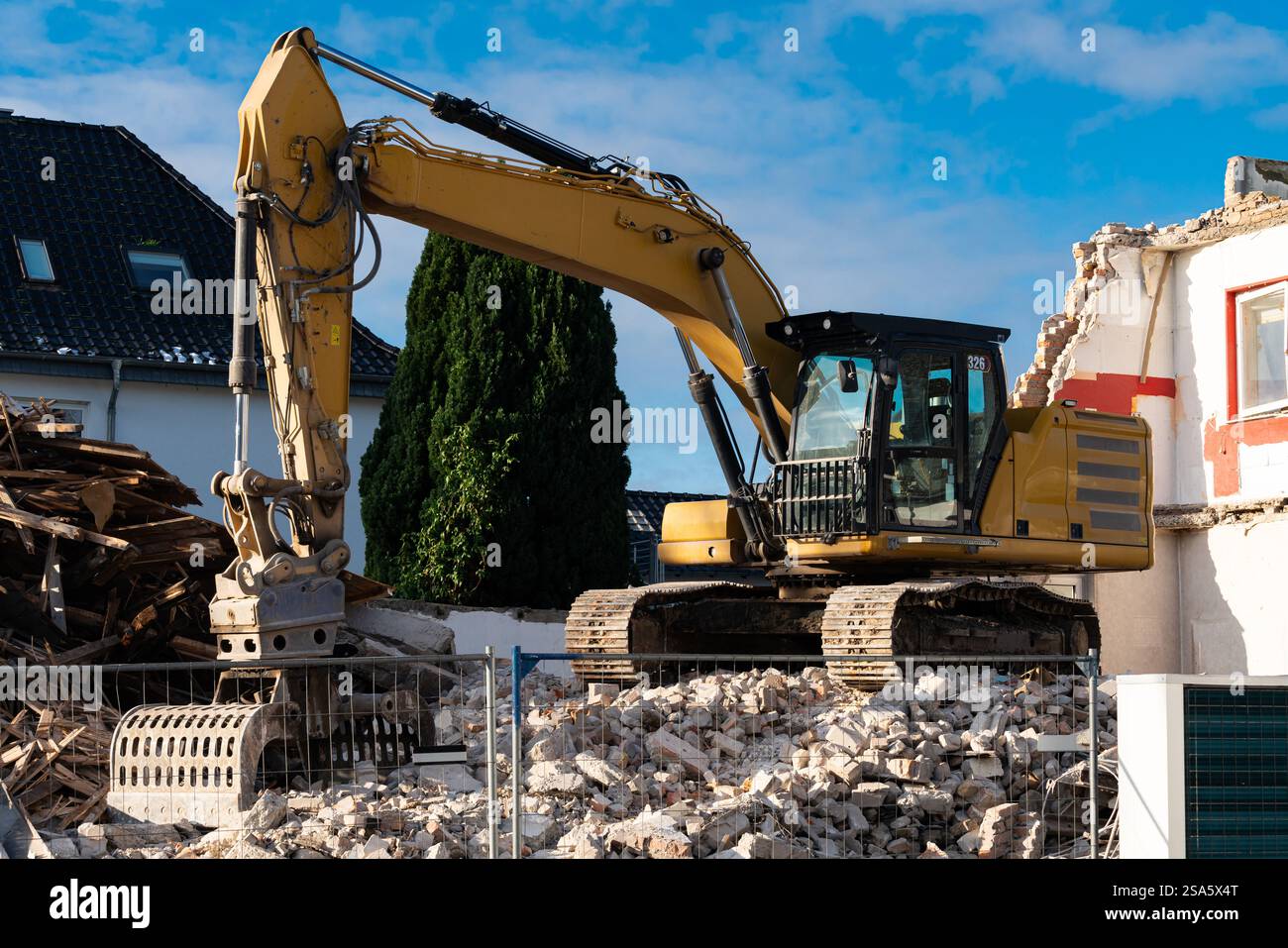 An excavator operates on a construction site, tearing down a damaged ...
