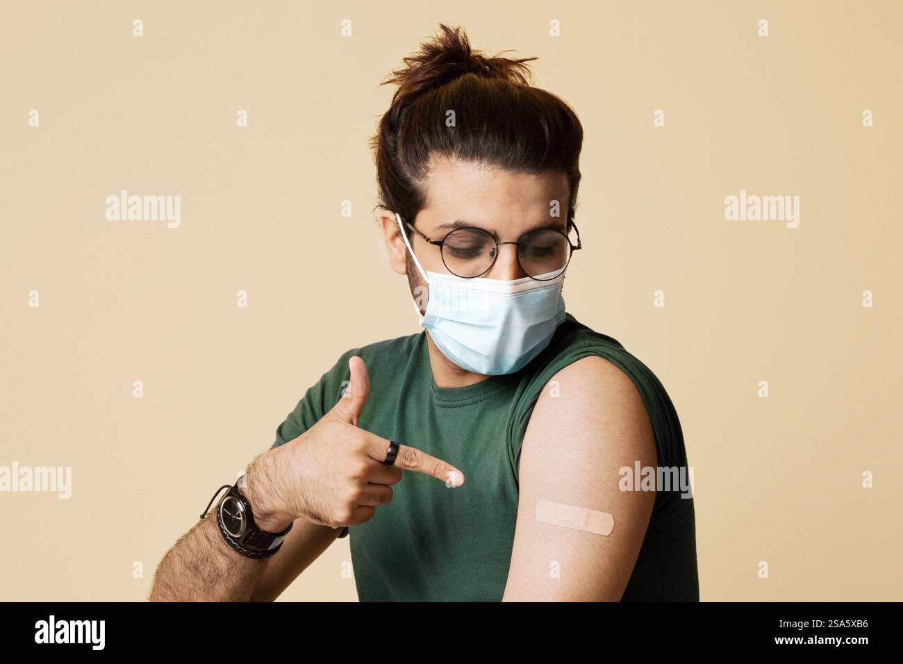 Arab guy in face mask pointing at plaster on shoulder Stock Photo - Alamy
