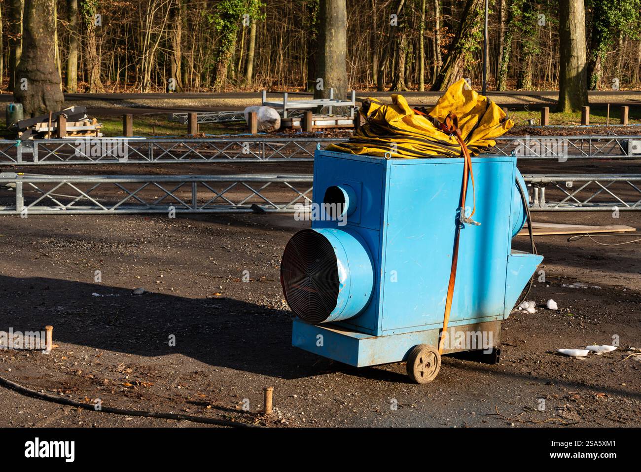 A blue portable air blower sits on a gravel surface, surrounded by ...