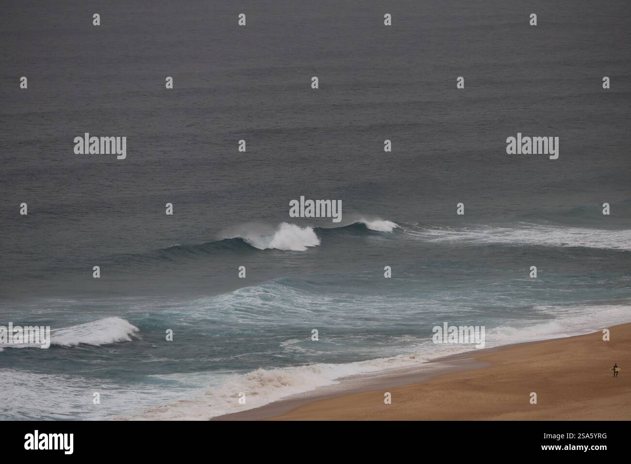 A surfer walking on Nazaré beach with waves.Nazaré.Portugal Stock Photo ...