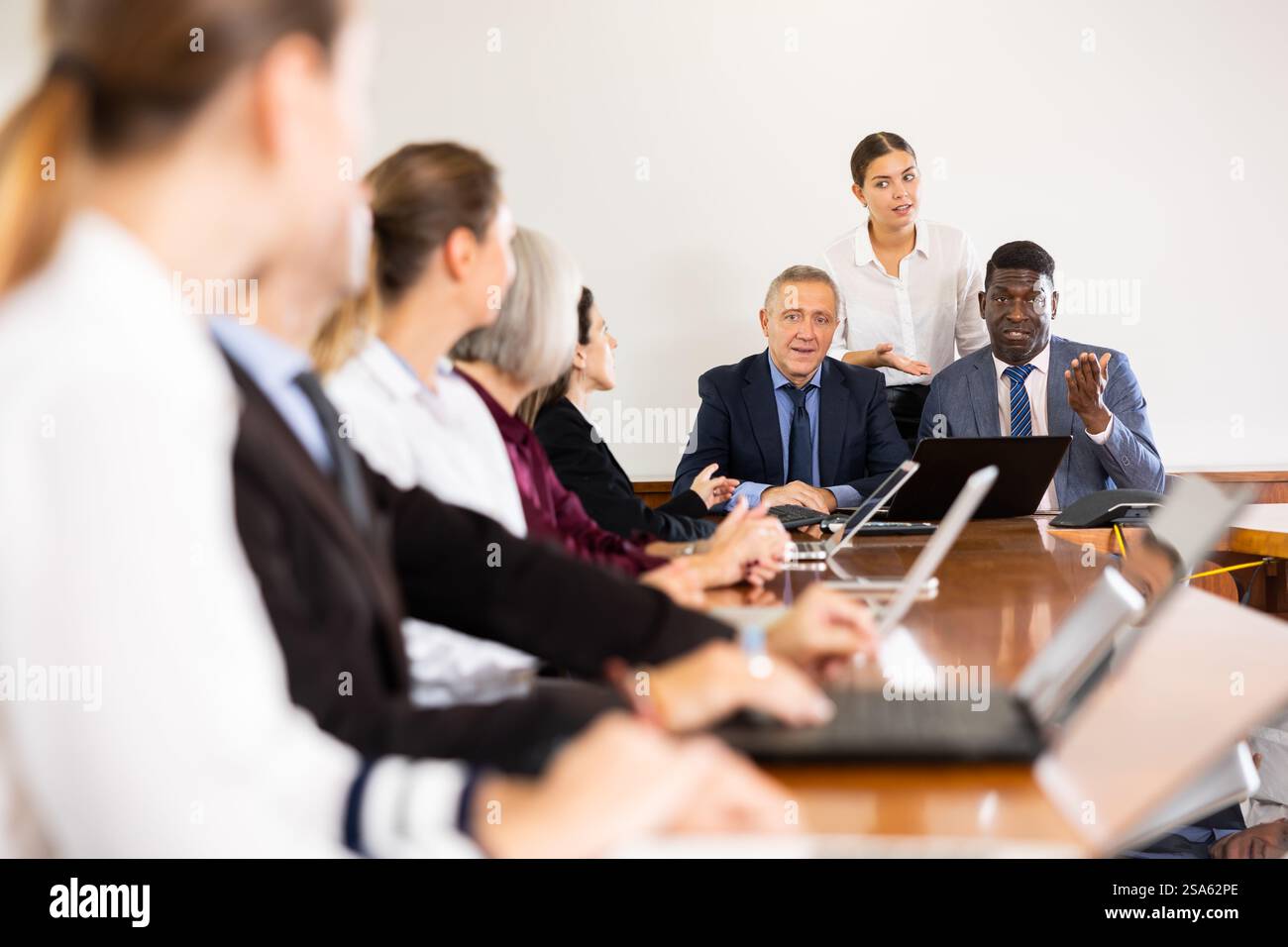 Female manager introduces new company executives to colleagues in ...
