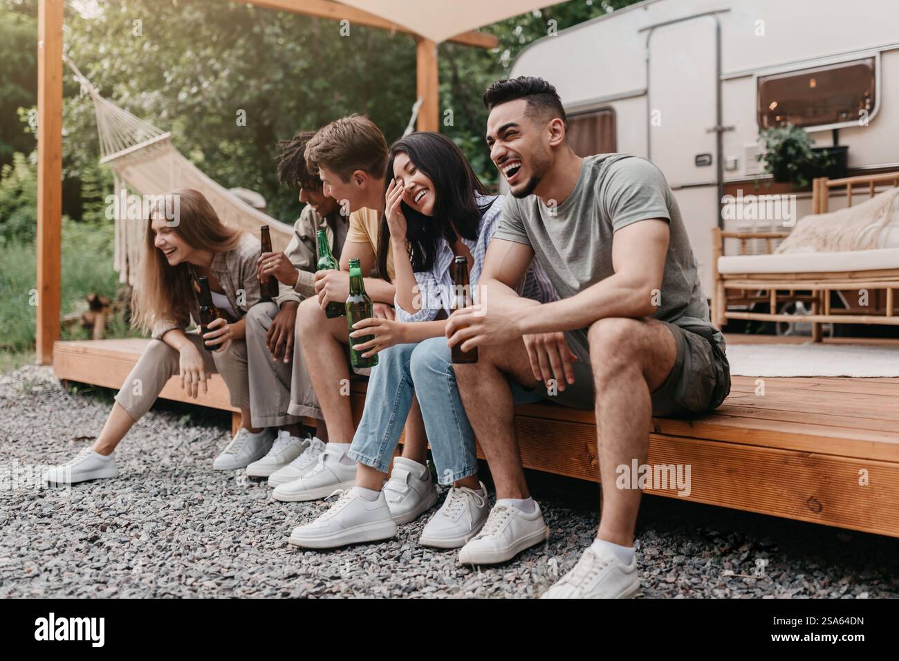 Happy multinational friends drinking beer, chatting and laughing ...