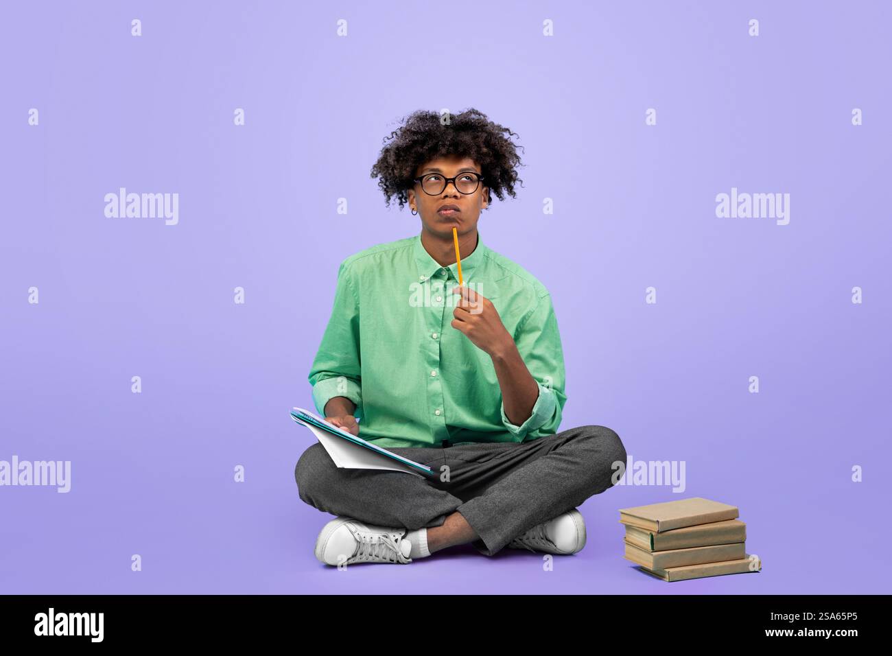 Thoughtful black guy student in glasses taking notes, holding notepad ...