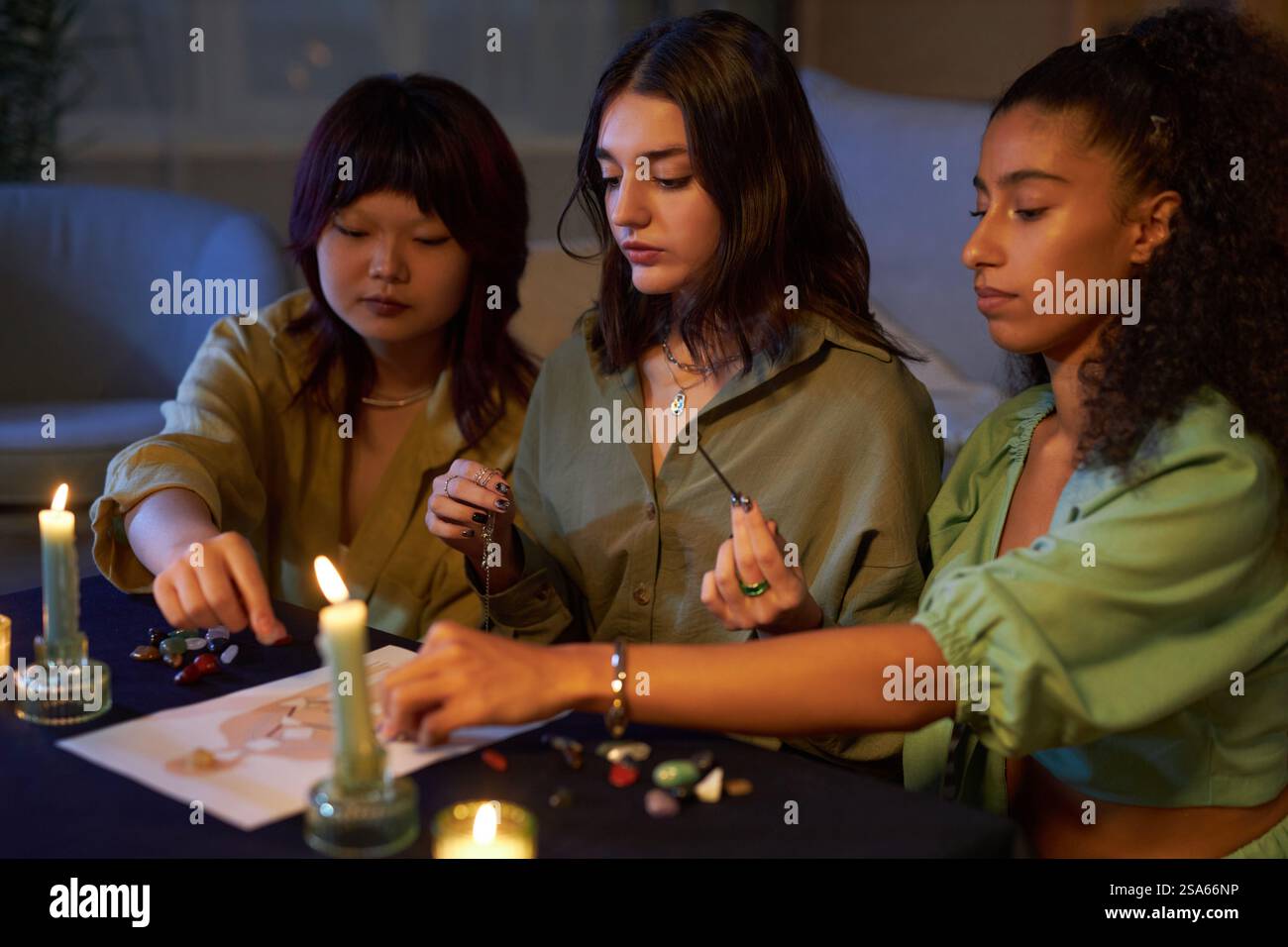 Three ethnically diverse gen Z girls sitting at coffee table in living ...