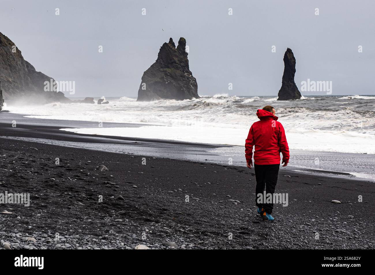 Traveler walking a majestic black sand beach Reynisfjara in Iceland in ...