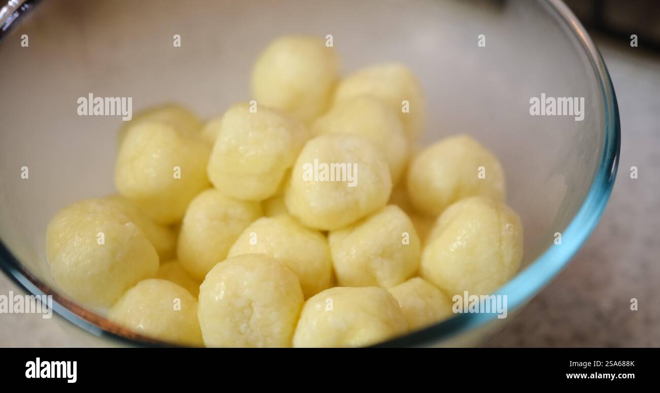 Spoon stirring hot dumplings in glass bowl with steam, set against ...