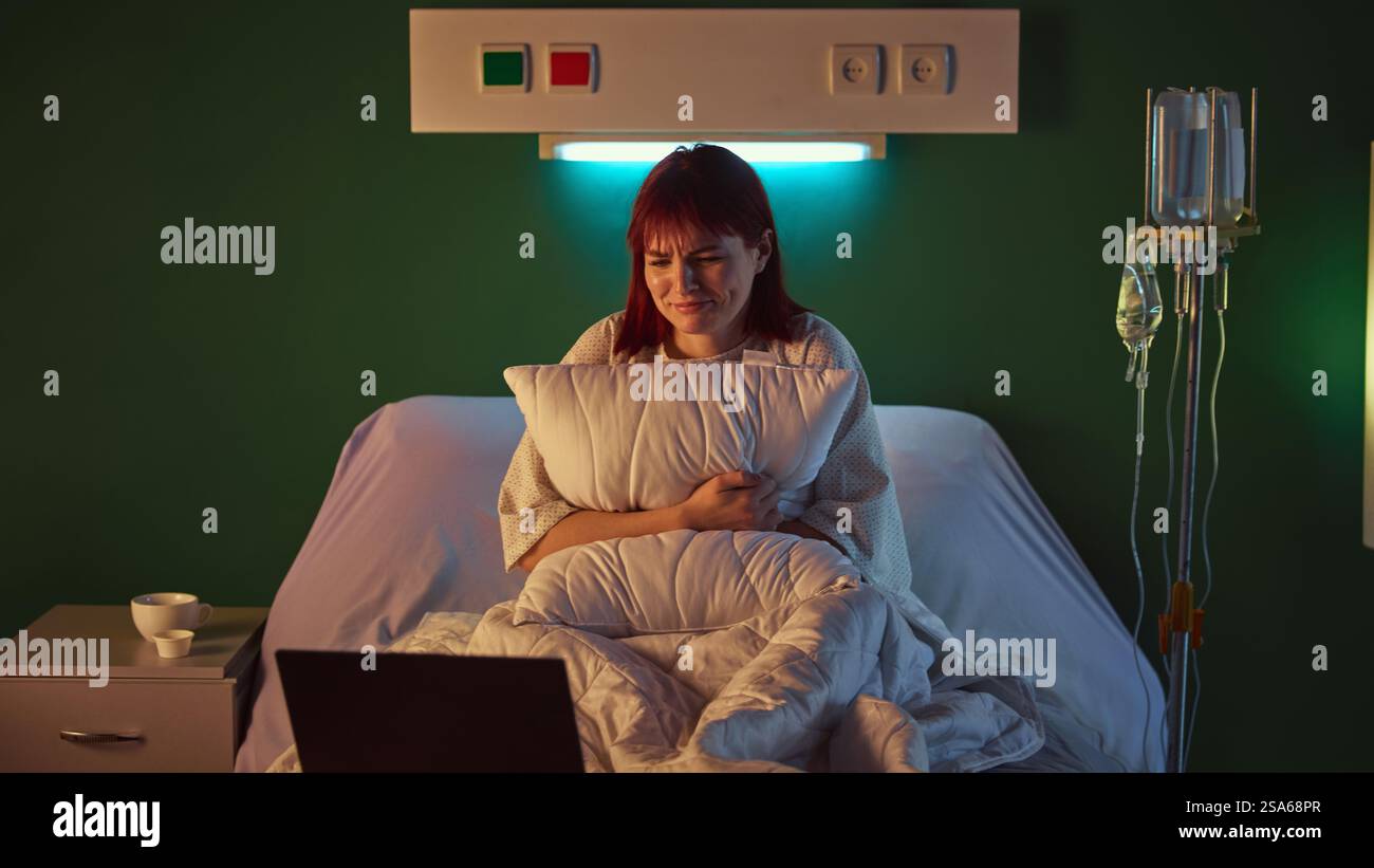 Young emotionally woman in hospital gown sitting in bed in hospital ...