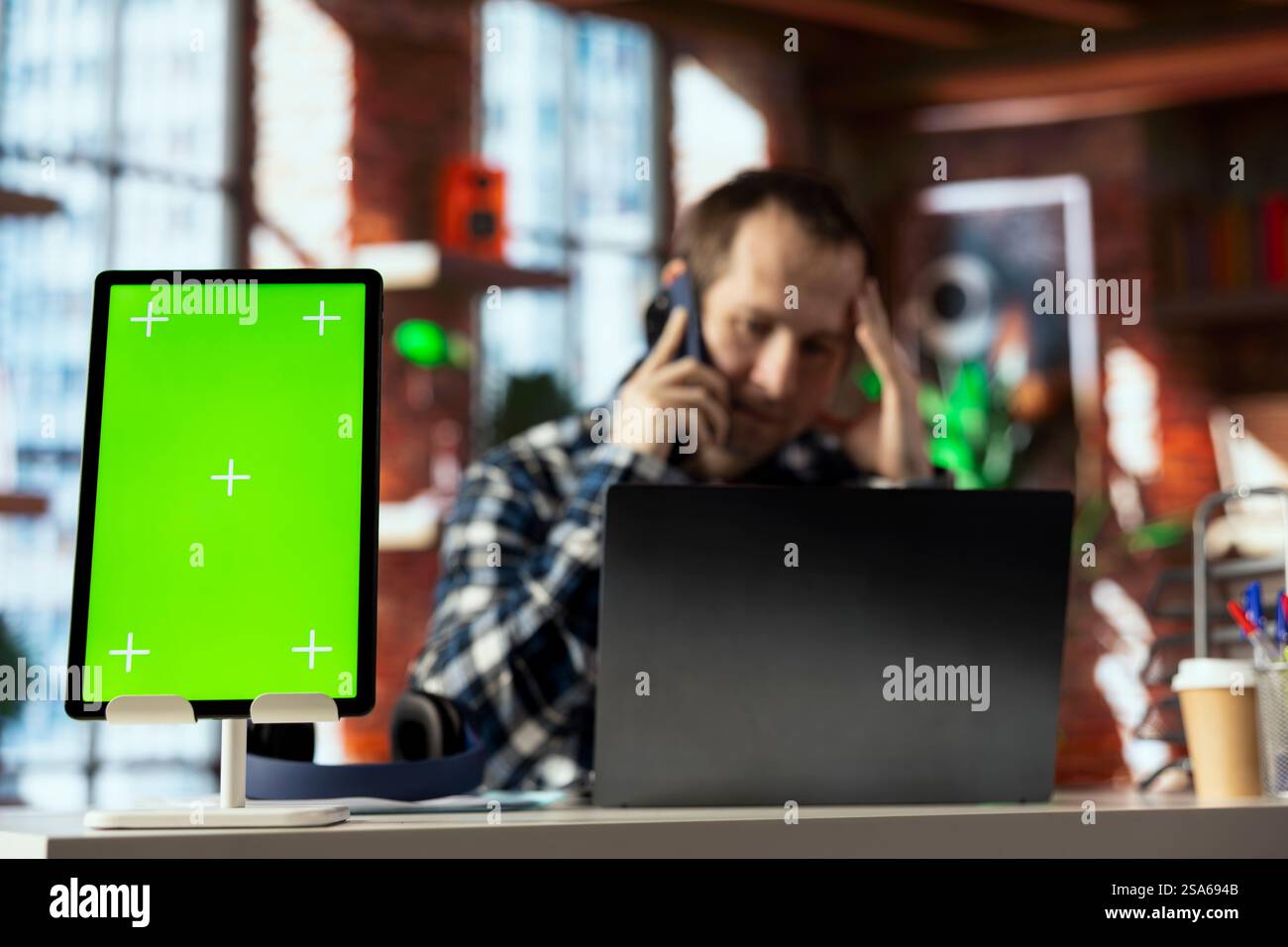 Close up of green screen tablet next to unhappy manager in telephone ...