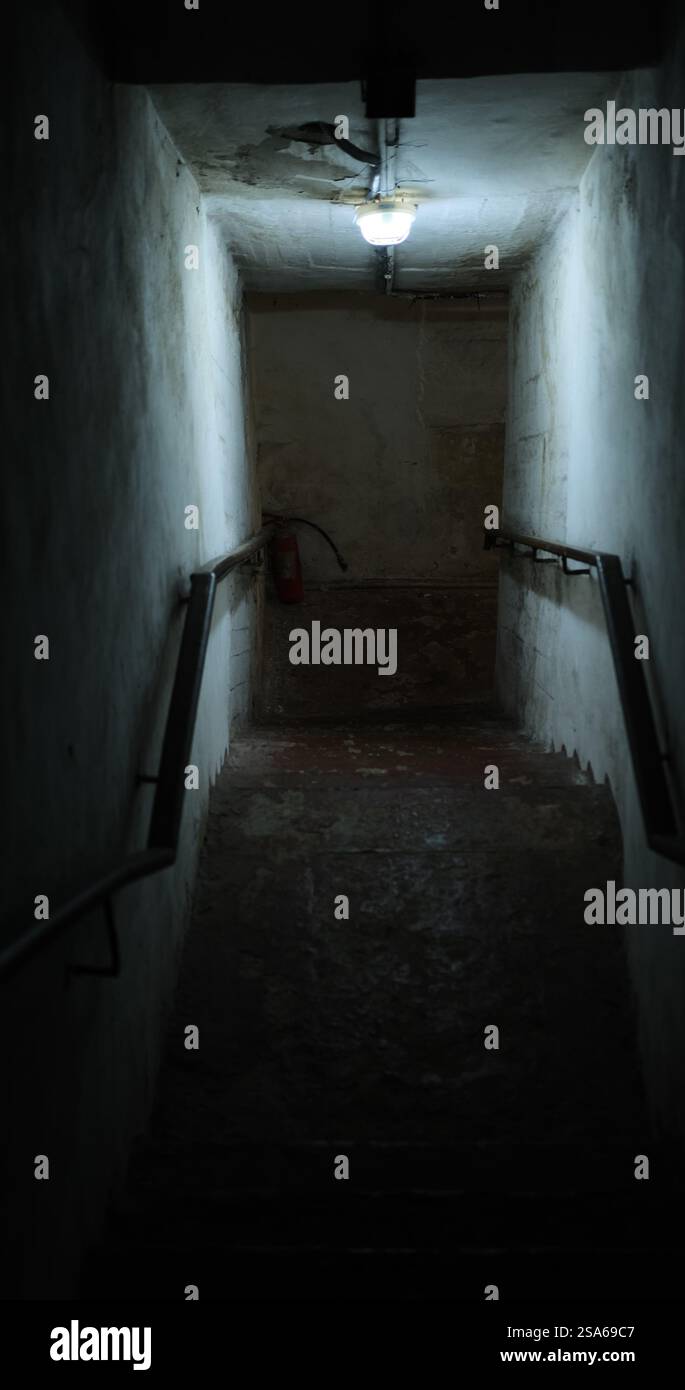 Dark old staircase in a bomb shelter with worn steps and dim lighting ...