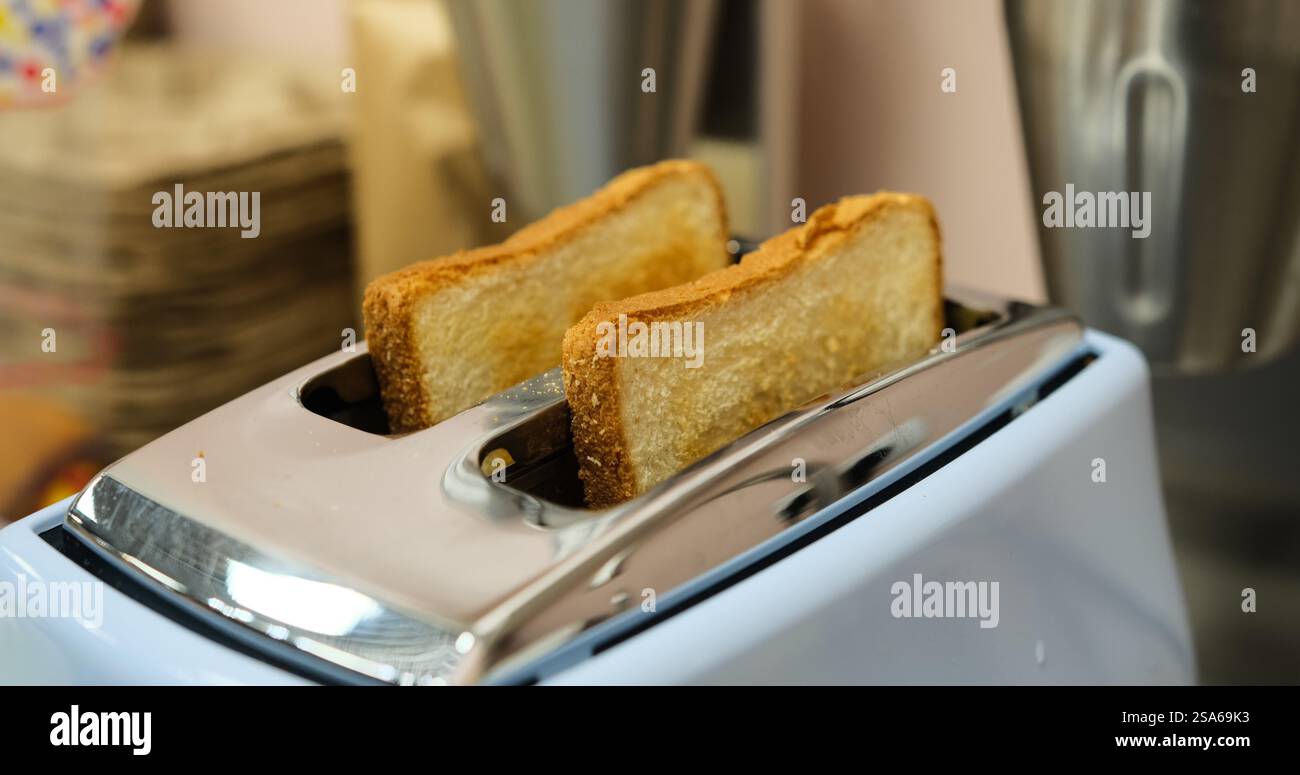 Golden toasted bread pops out of a blue toaster with a crispy texture ...