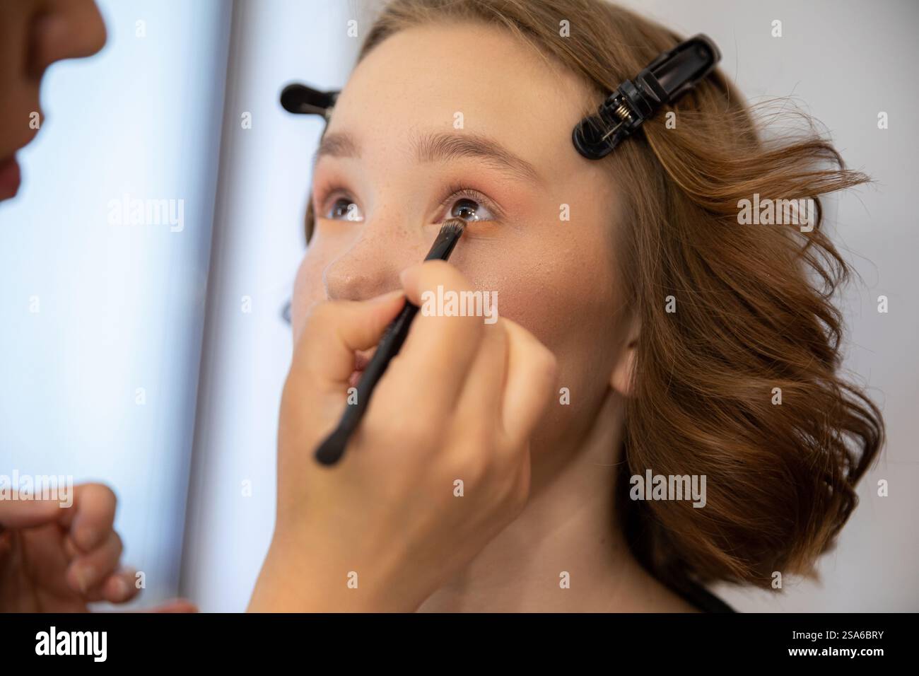 A skilled Makeup Artist is meticulously applying eye makeup on a ...