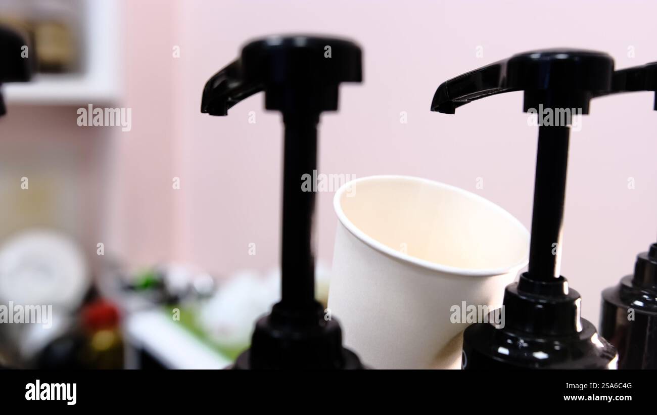 Barista adds red cherry syrup to a white paper coffee cup using a ...