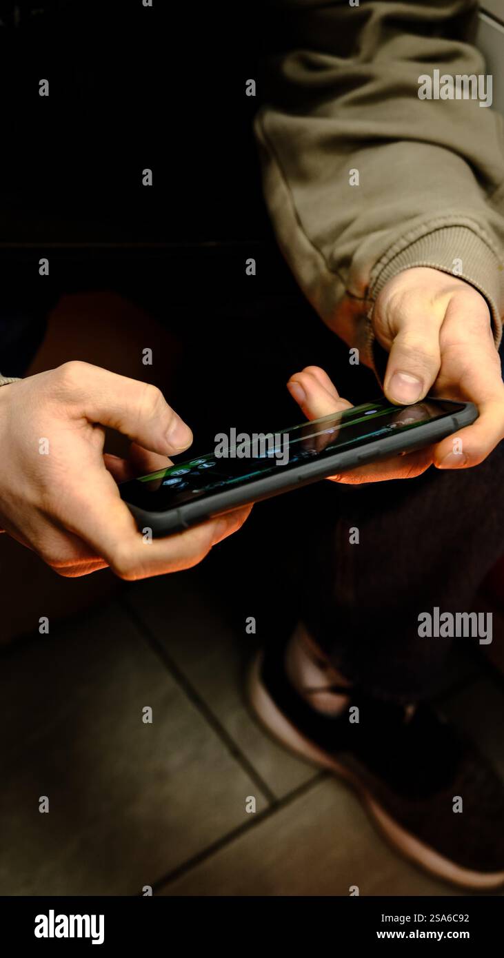 young man playing mobile game with rapid finger movements, hands ...