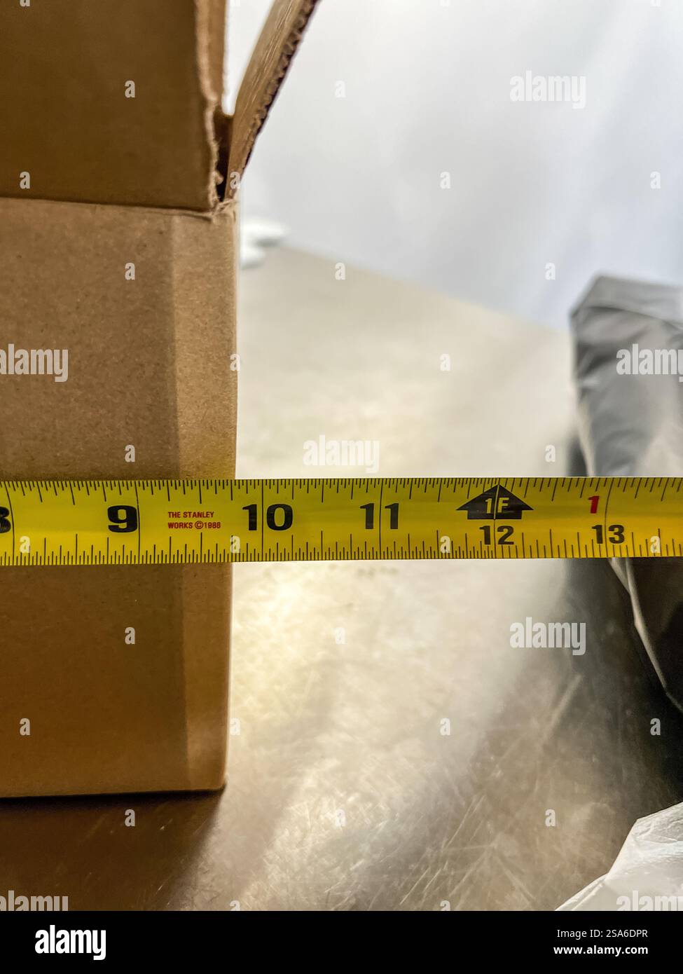 Measuring cardboard box dimensions with tape measure Stock Photo - Alamy
