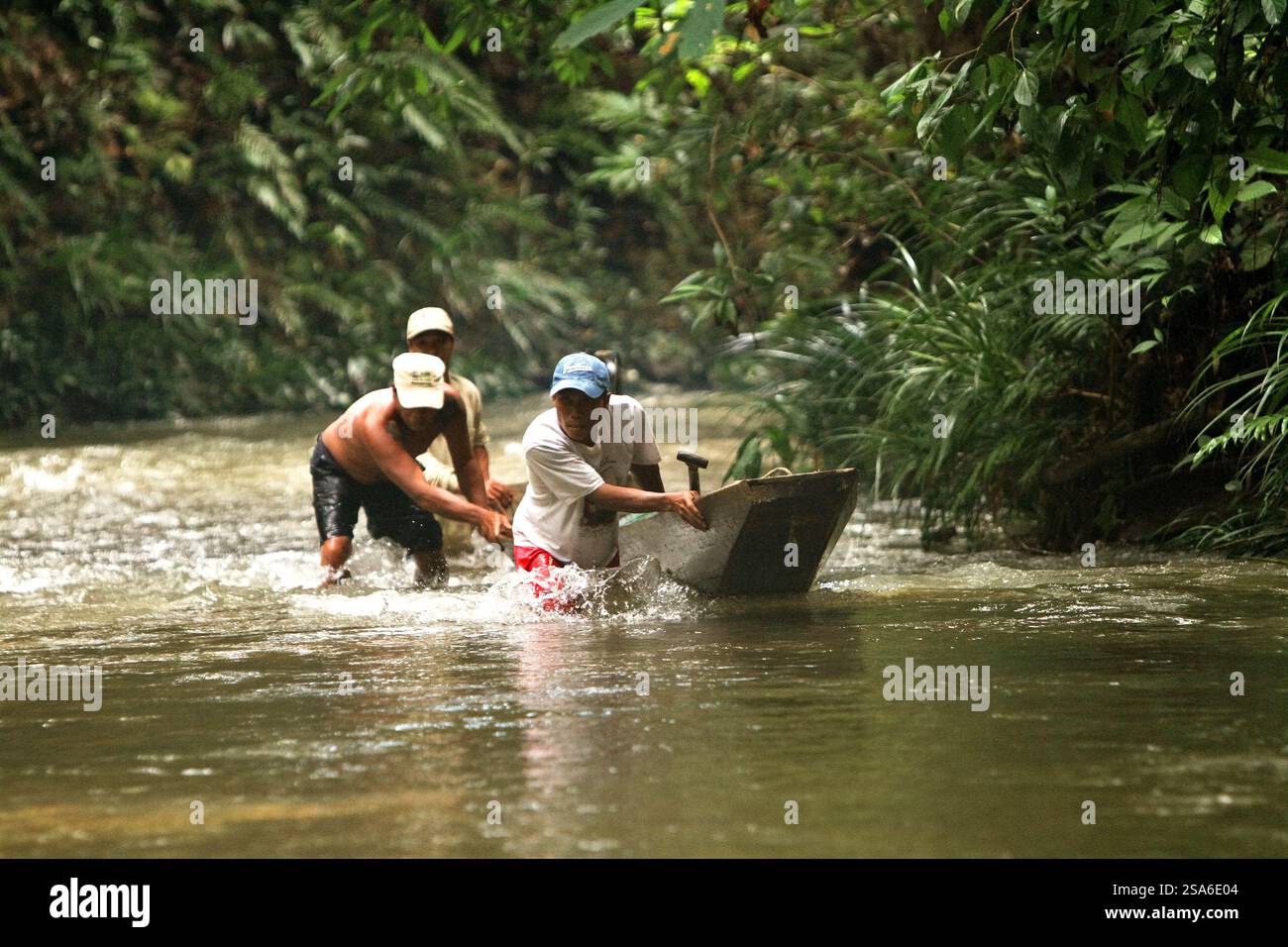 Men pushing a boat to move on shallow water in the river, across the ...
