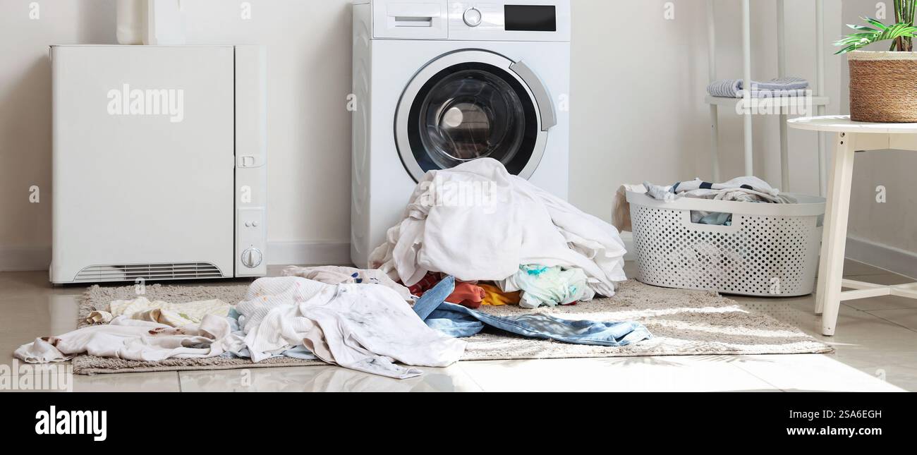 Interior of light laundry room with modern washing machine and pile of ...
