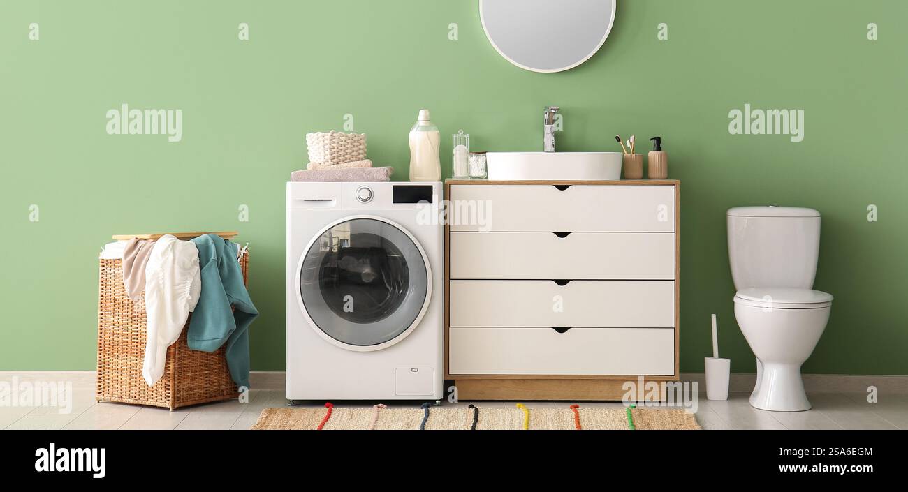 Modern washing machine, toilet bowl, chest of drawers and basket with ...