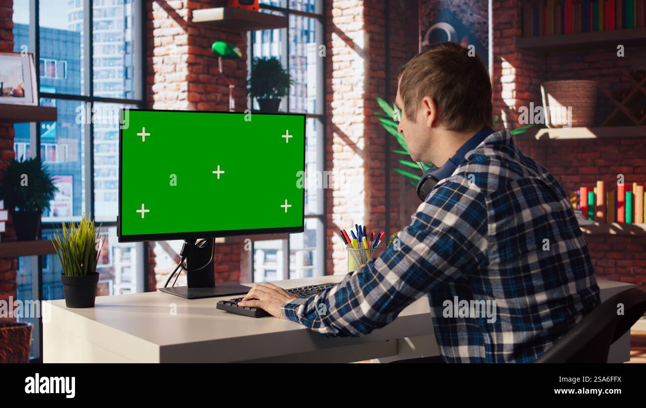Teleworking man in living room home office using chroma key computer to plan business ...