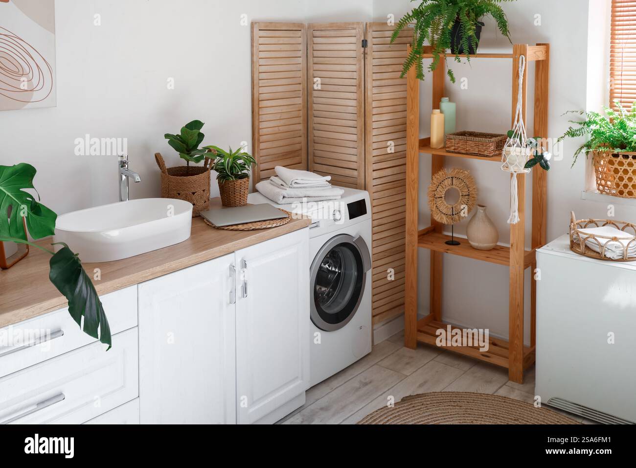 Interior of stylish laundry room with washing machine, sink and laptop ...