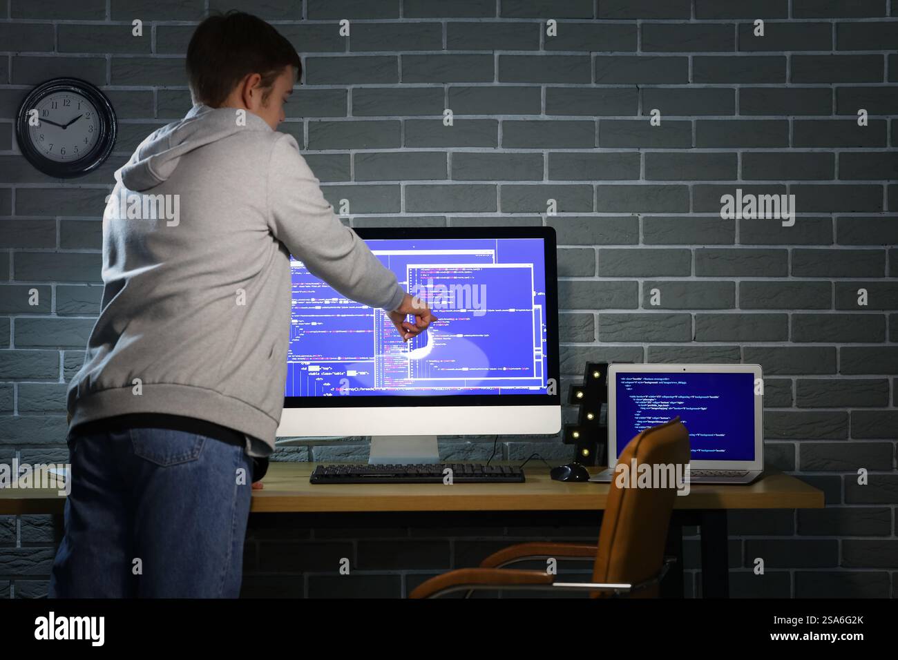 Hacker pointing at computer screen in dark room, back view Stock Photo ...