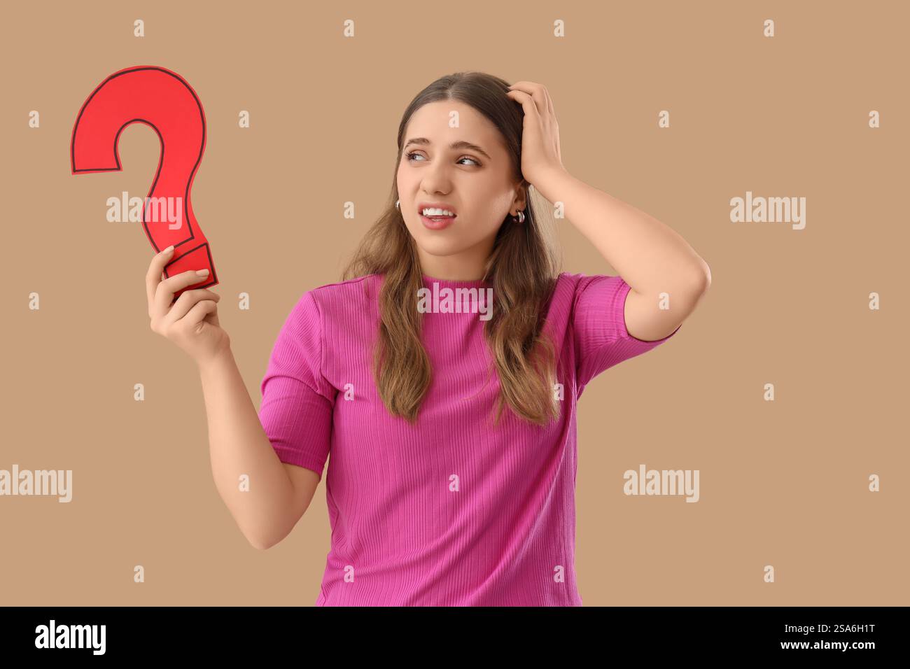 Thoughtful woman holding question mark on beige background Stock Photo ...