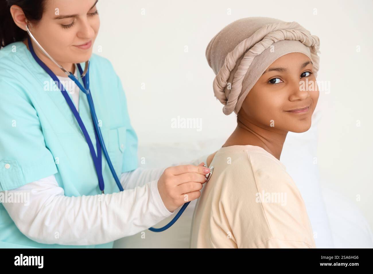 Female doctor with stethoscope listening to African-American girl after ...