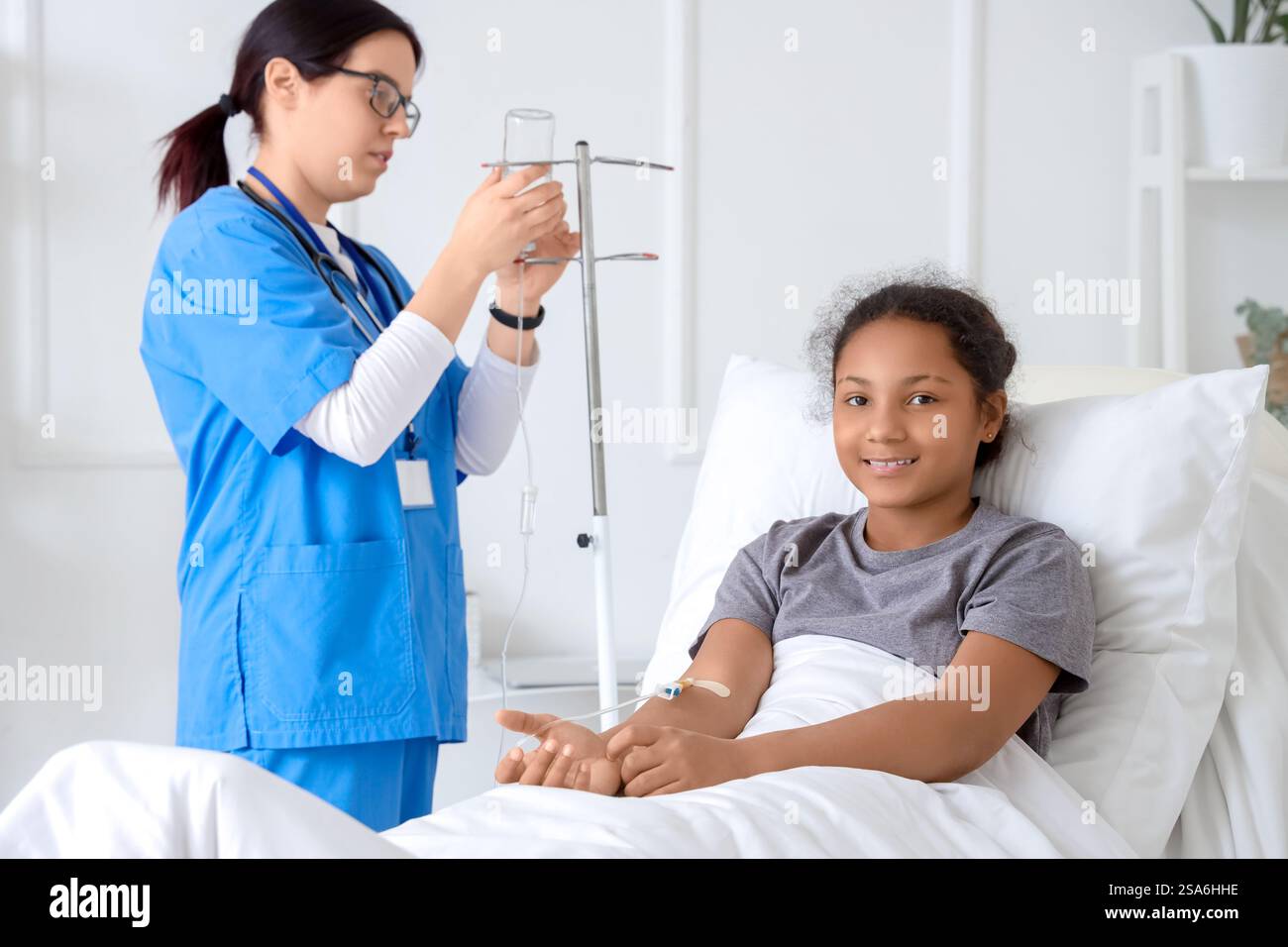 Teenage African-American girl with infusion drip and doctor in hospital ...