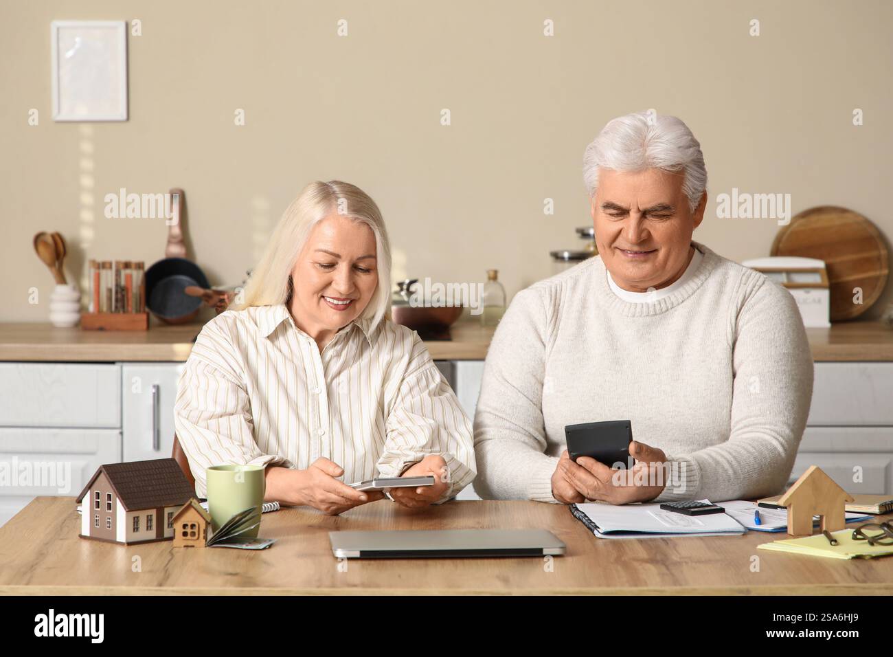 Happy senior couple calculating utility bills at table in kitchen Stock ...