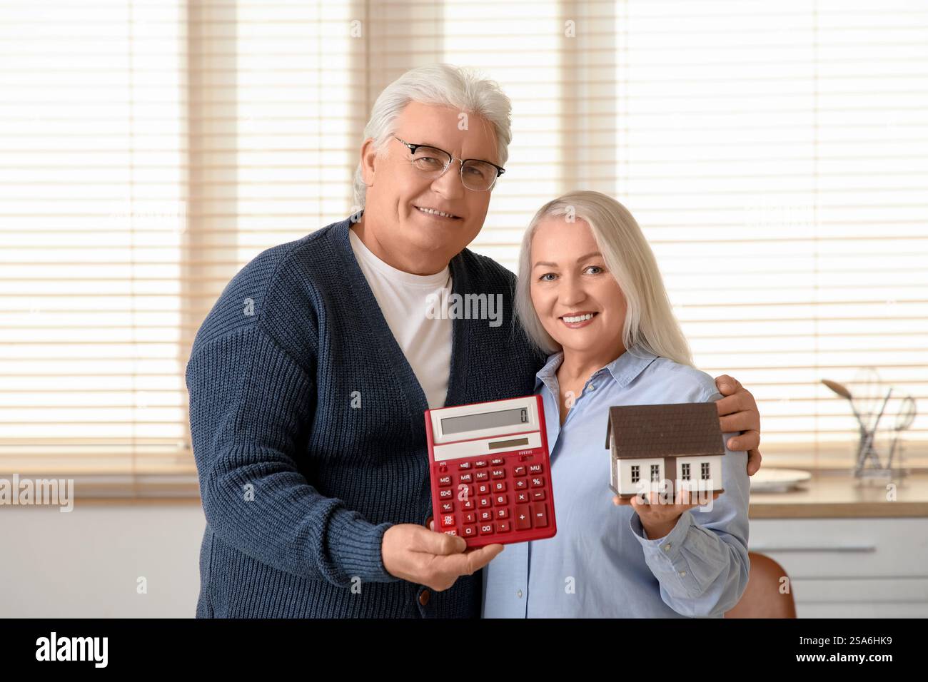 Senior couple with calculator and house model in kitchen Stock Photo ...