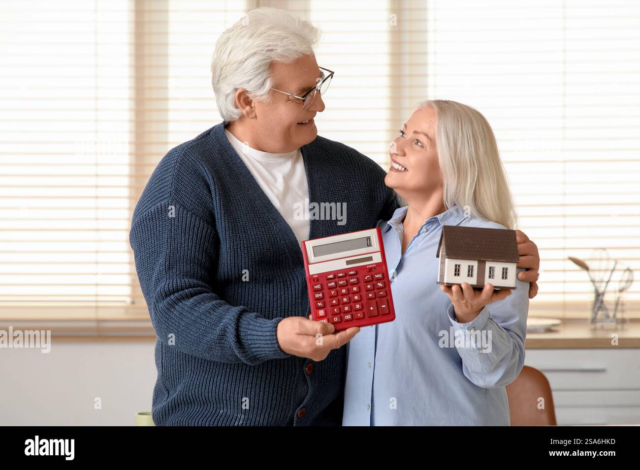 Senior couple with calculator and house model in kitchen Stock Photo ...