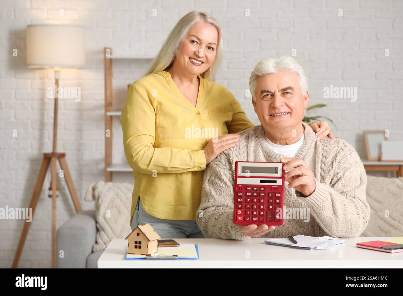 Senior man with his wife calculating utility bills on table at home ...