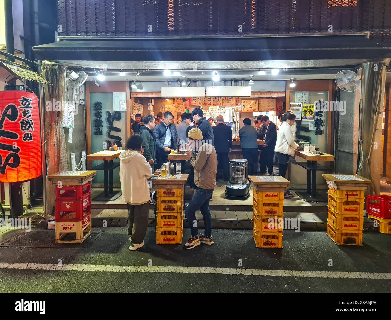 Crowded Tokyo restaurant bar at night with empty crates as tables in ...